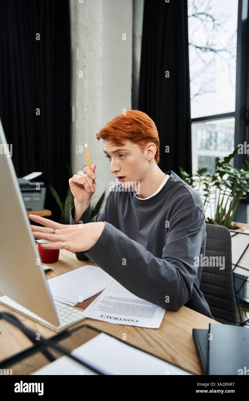 Dedicated young man with red hair collaborates on tasks at a ...