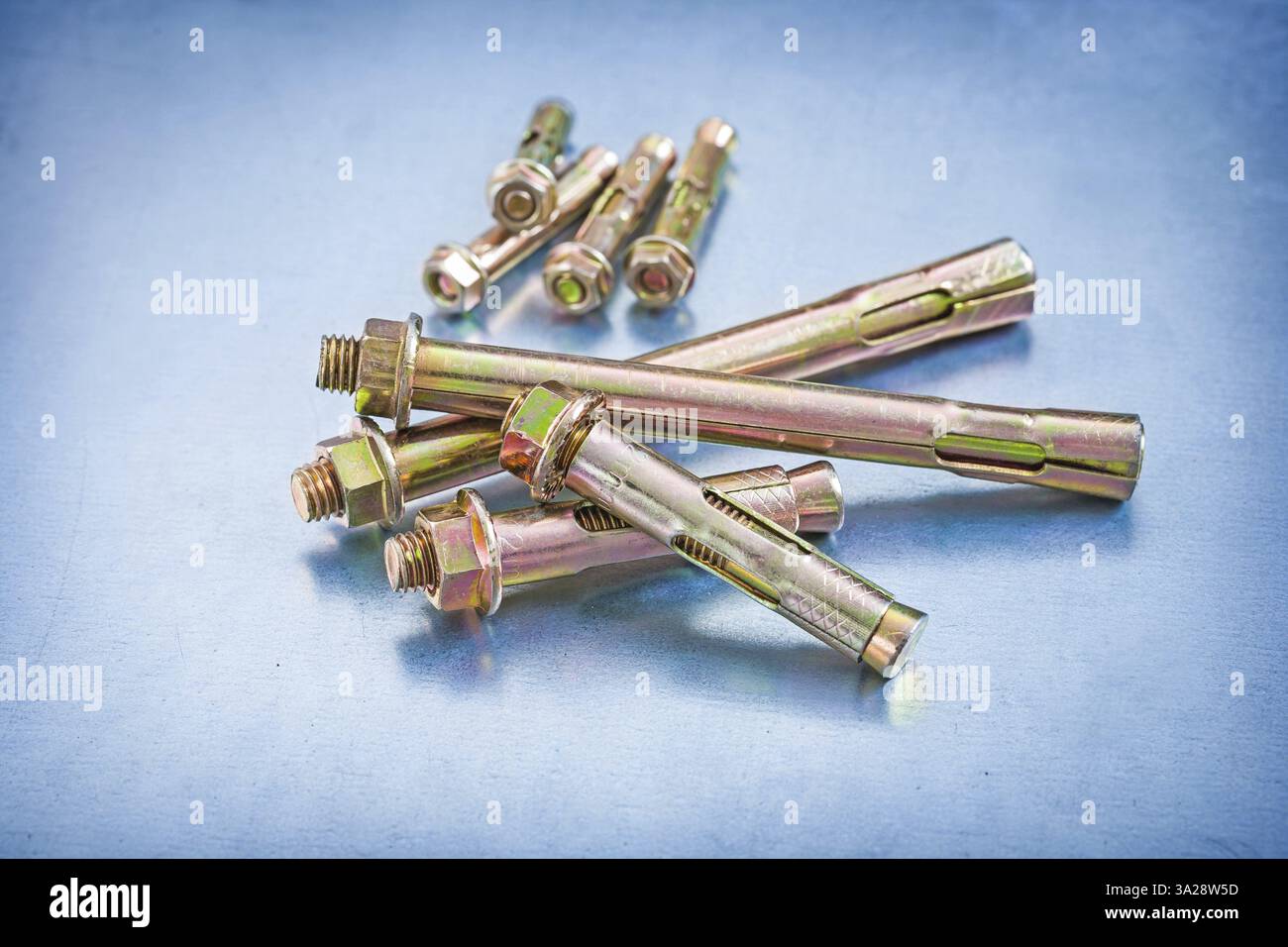 Set of metal anchor bolts with construction nuts on metallic background ...