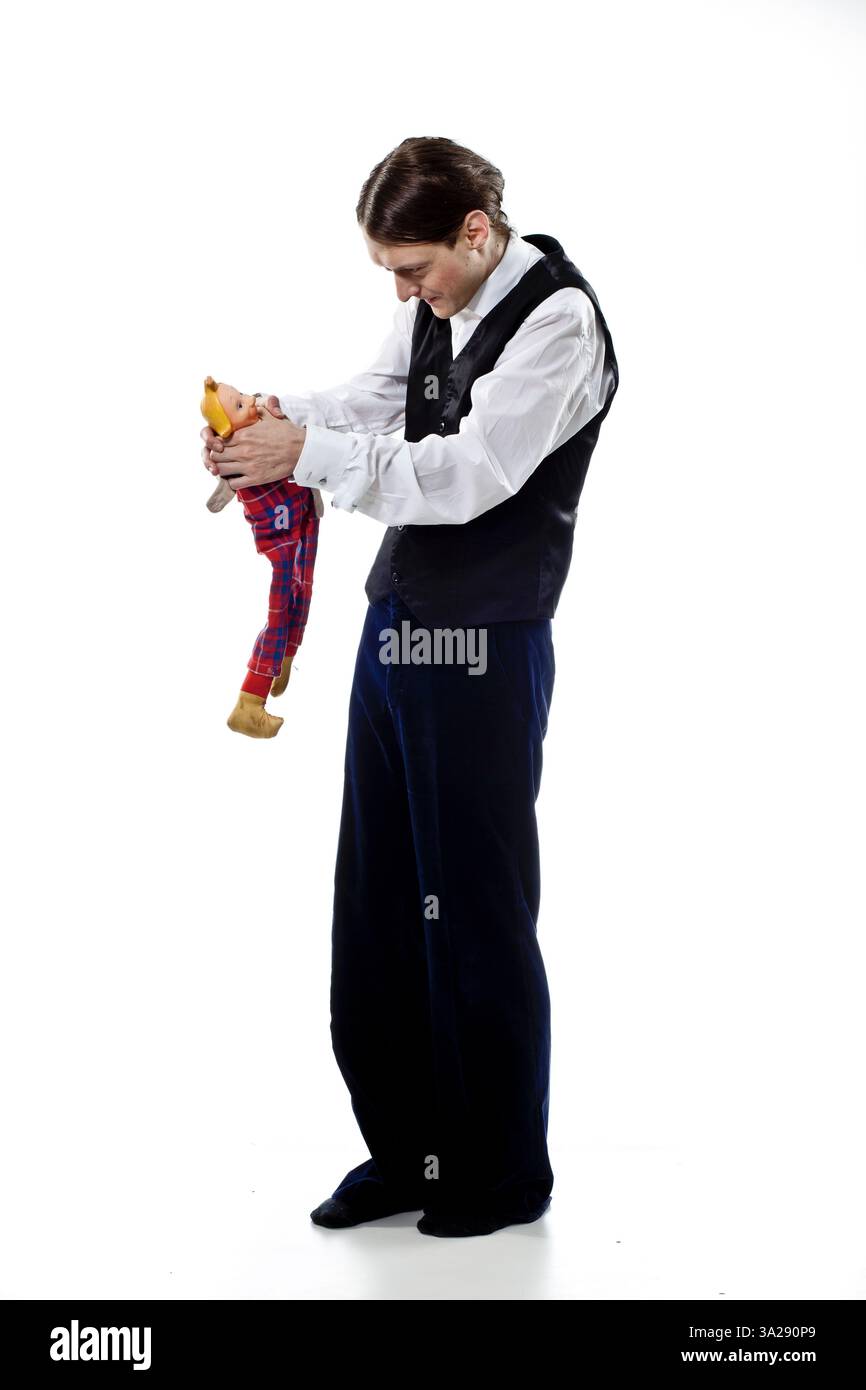 A man in formal attire, wearing a black vest and white shirt, stands ...