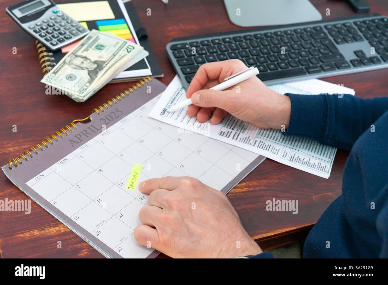A person filling out a U.S. tax form, the hand is signaling the day of ...