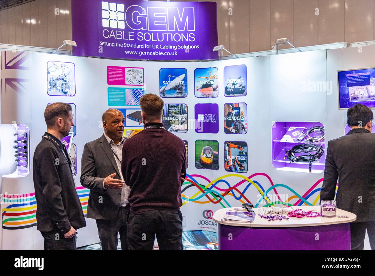 People talking at a Gem Cable Solutions stall at the Space Comm Expo ...