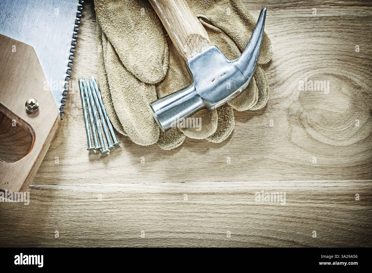 Set of claw hammer safety gloves handsaw nails on wooden board ...