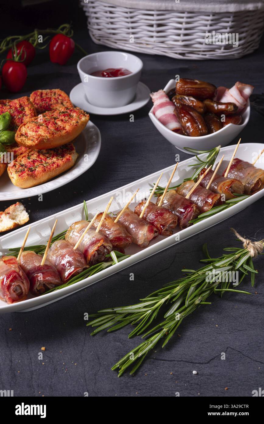 Dates wrapped in bacon and delicious tapas Stock Photo - Alamy