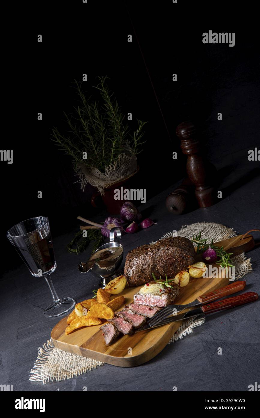 Rustic medium rare beef steak with herbs and potato wedges Stock Photo - Alamy