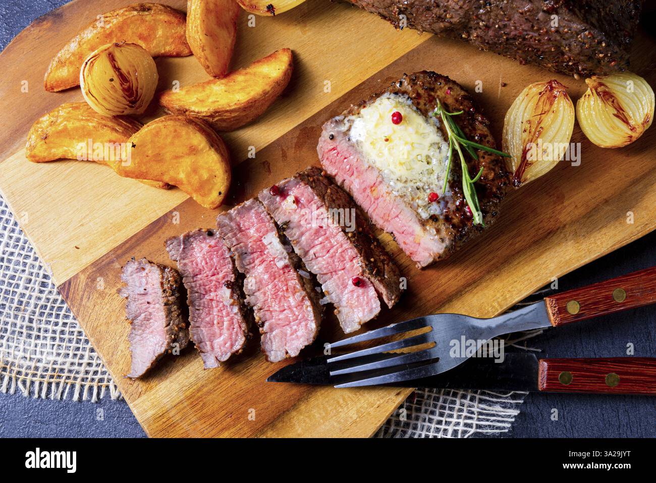 Rustic medium rare beef steak with herbs and potato wedges Stock Photo - Alamy