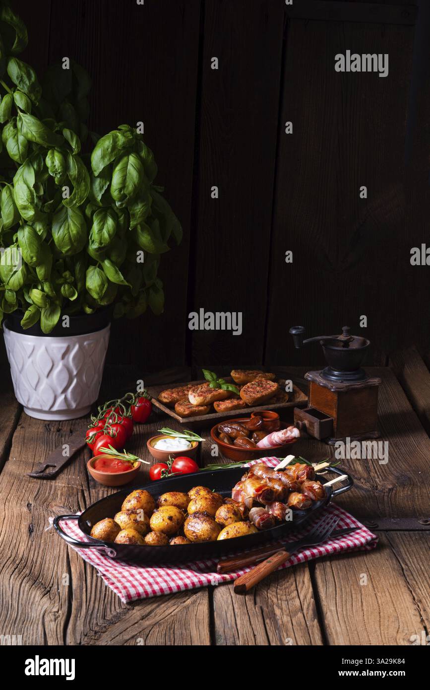Rustic dates wrapped in bacon and young roasted potato Stock Photo - Alamy