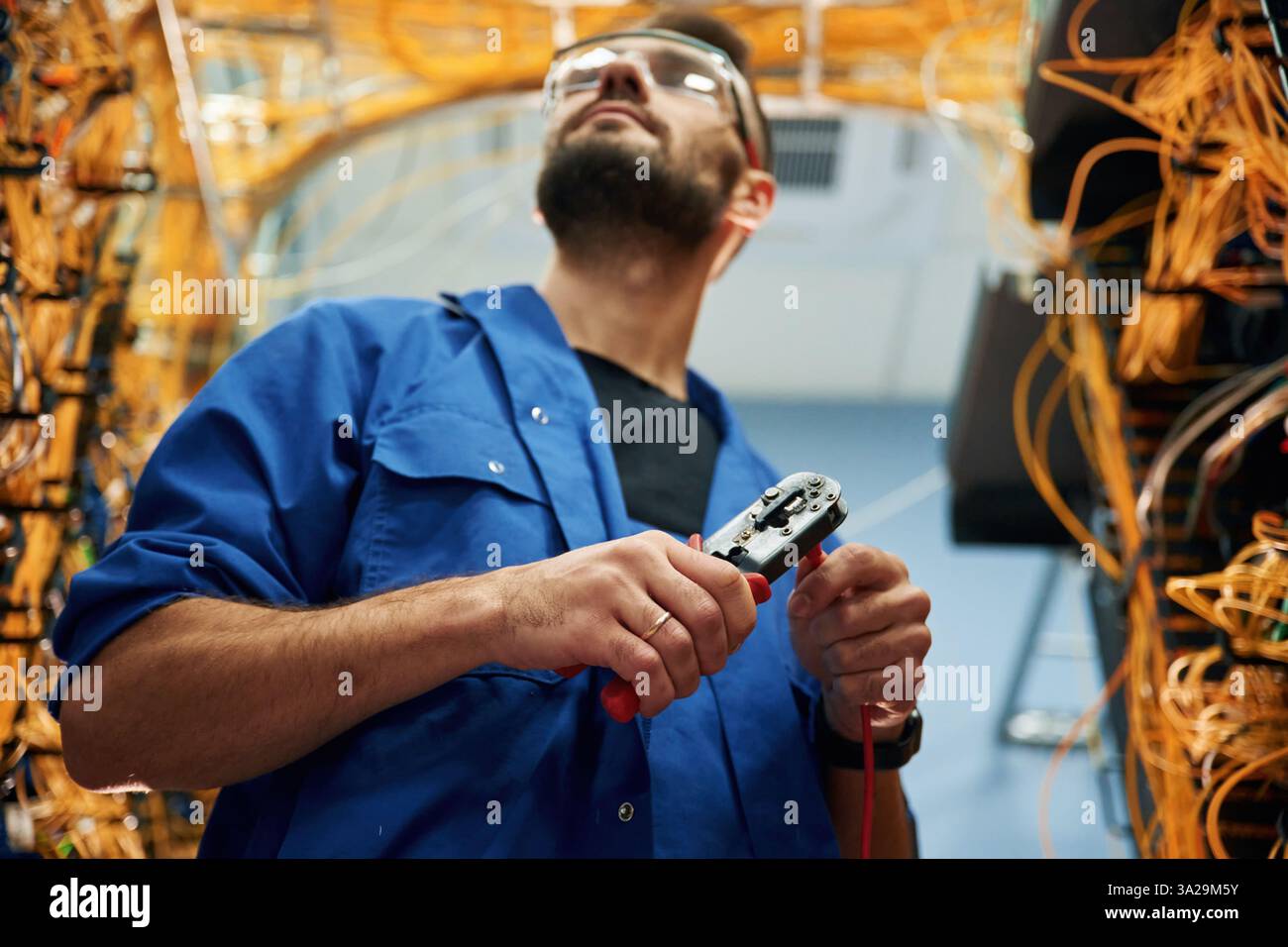 Busy by cutting the wire. Young man is working with internet equipment ...