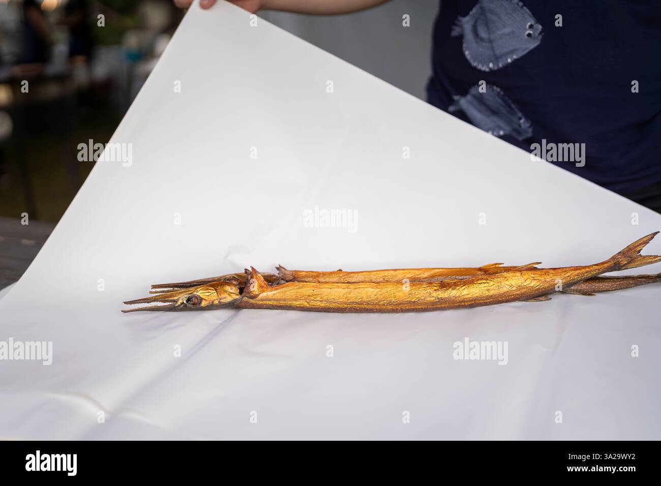 Smoked garfish on a white wrapping paper. Smoked seafood fish ...