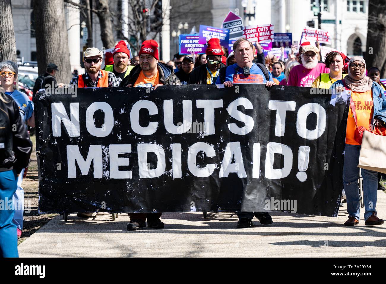 People with a banner saying "No cuts to Medicaid!" at a rally to save ...