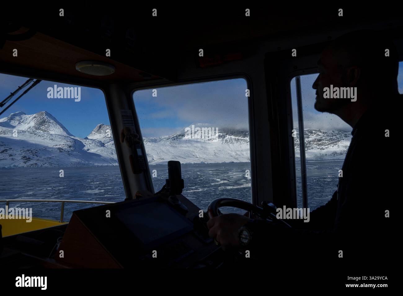 A boat captain rides though a frozen sea inlet outside of Nuuk ...
