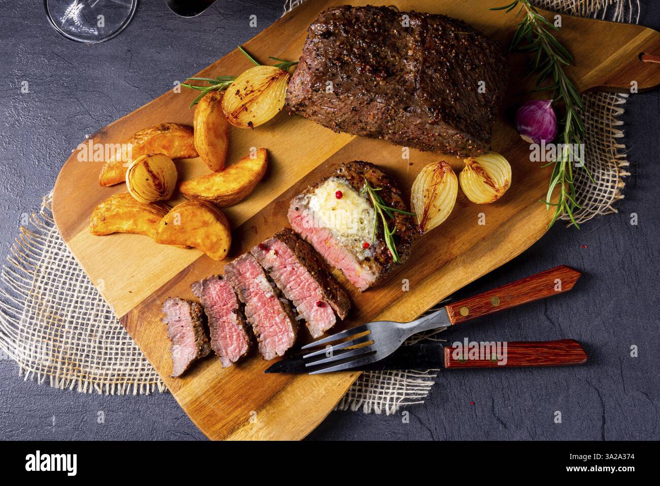 Rustic medium rare beef steak with herbs and potato wedges Stock Photo - Alamy