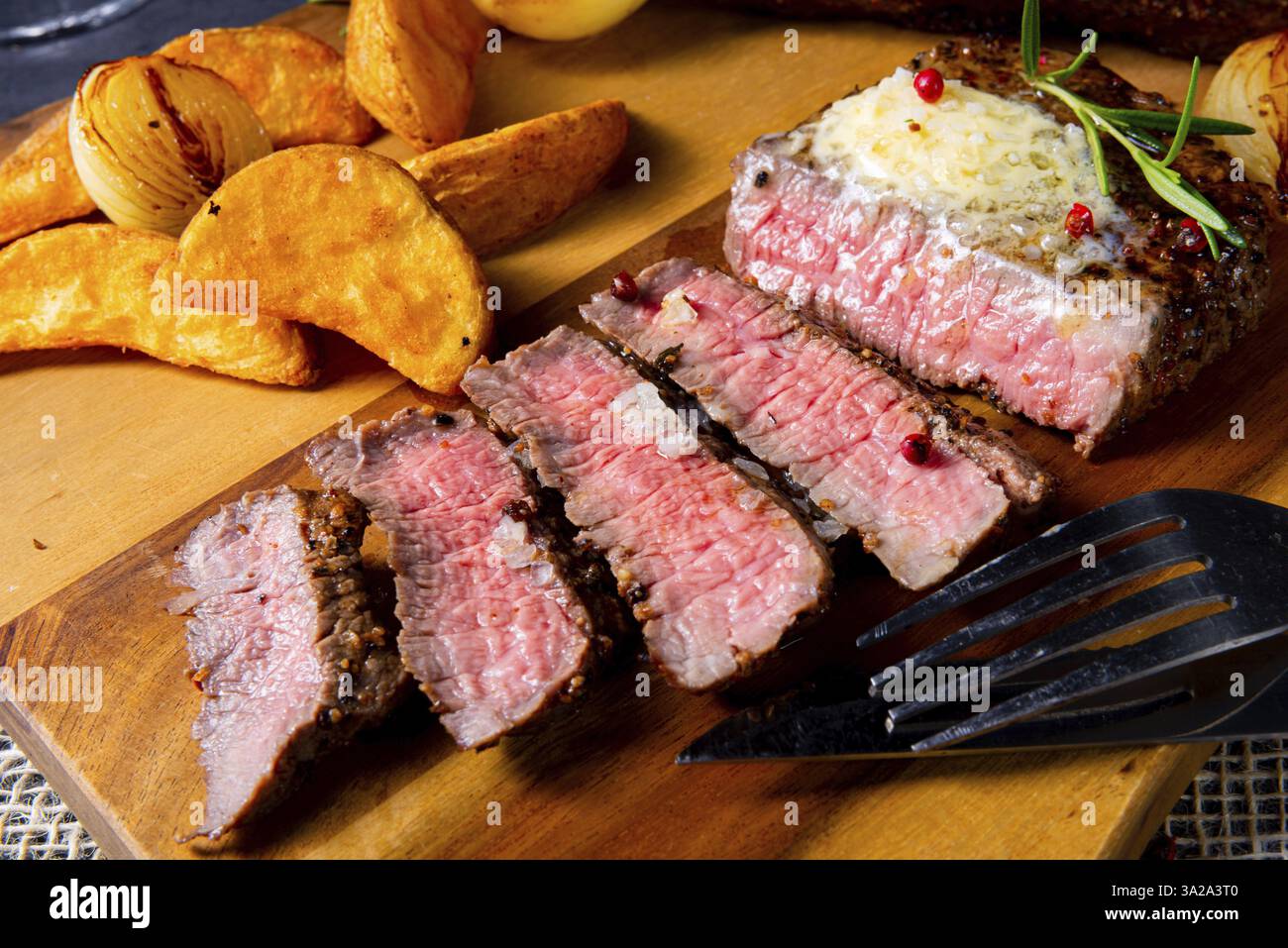 Rustic medium rare beef steak with herbs and potato wedges Stock Photo - Alamy