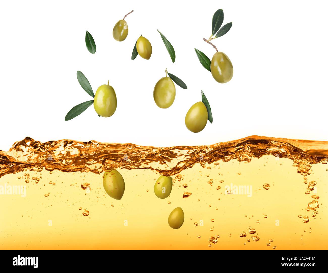 Green olives and leaves falling into cooking oil on white background ...