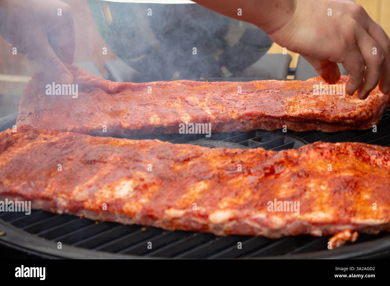 A view of a hands placing pork ribs on the grill Stock Photo - Alamy