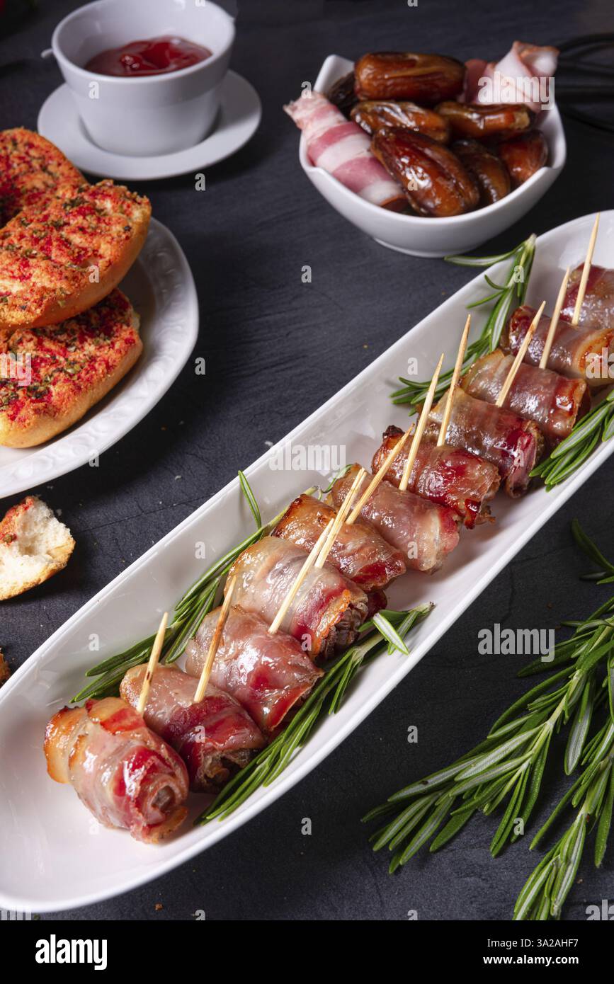 Dates wrapped in bacon and delicious tapas Stock Photo - Alamy