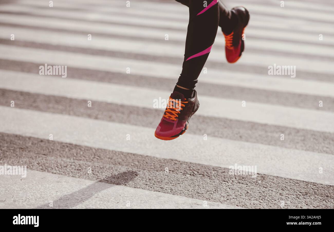 Jump and freeze in air. Girl in sportswear and sneakers runs along ...