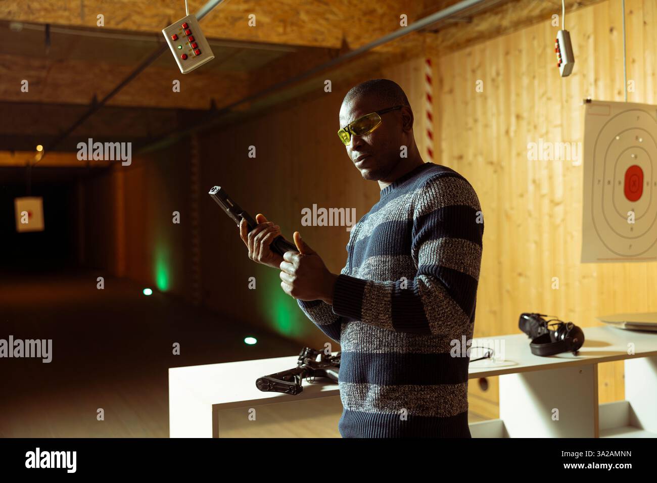 Man wearing protective goggles reloading gun with bullets in shooting ...