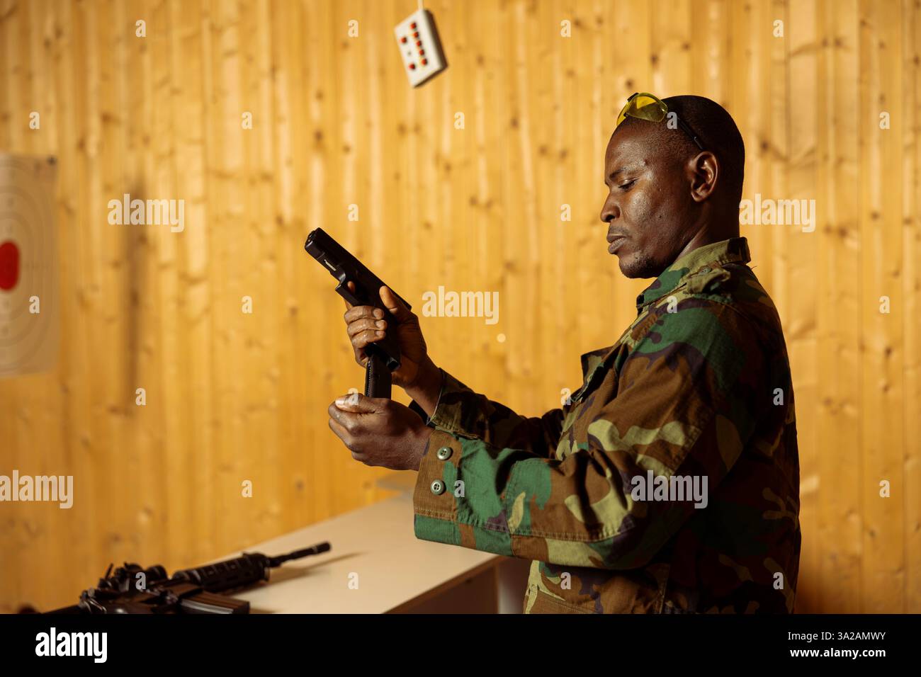 Army soldier wearing protective gear reloading handgun in indoor ...