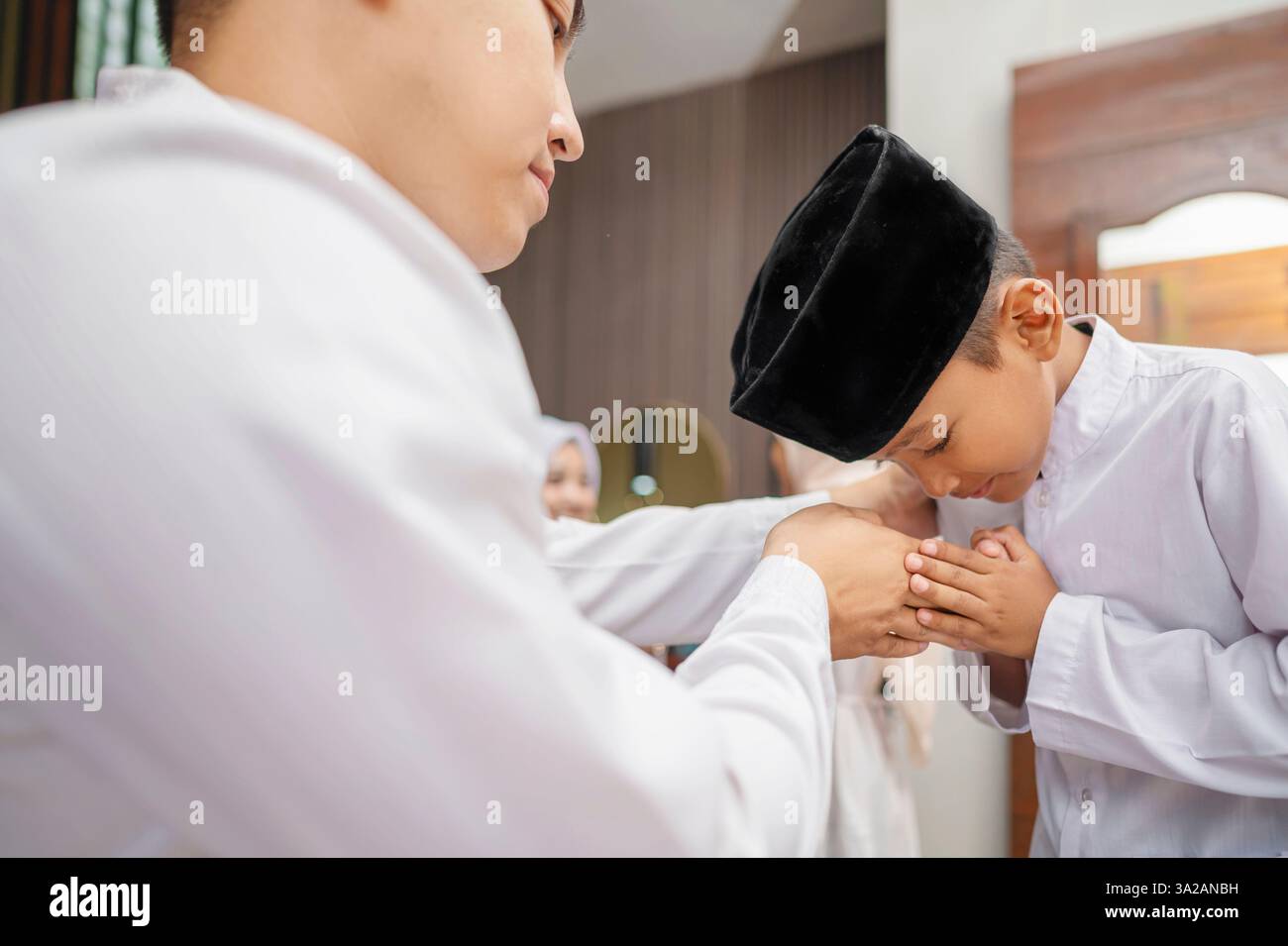 Portrait of the Indonesian Muslim boy asking forgiveness to his father while celebrating Eid ...
