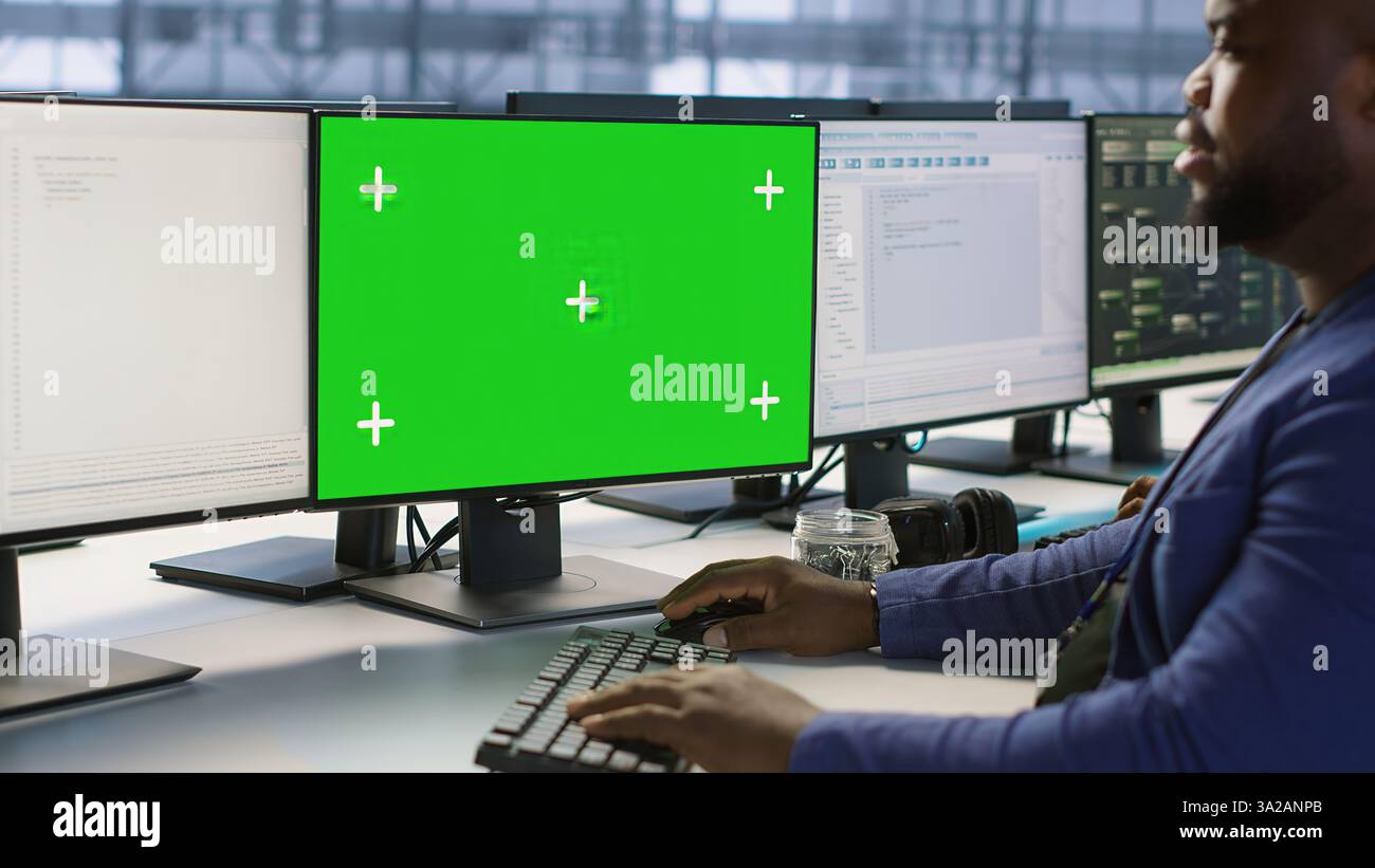 Engineer using green screen computer in server room, developing disaster recovery plans ensuring ...