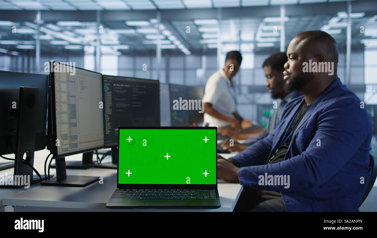 Employees using green screen laptop, working in server farm to optimize it for data processing ...