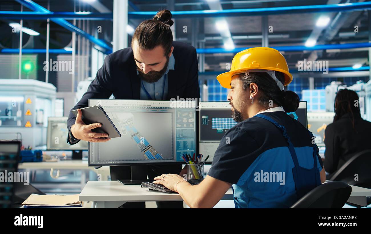 Solar panel manufacturing plant expert using tablet to show worker how ...