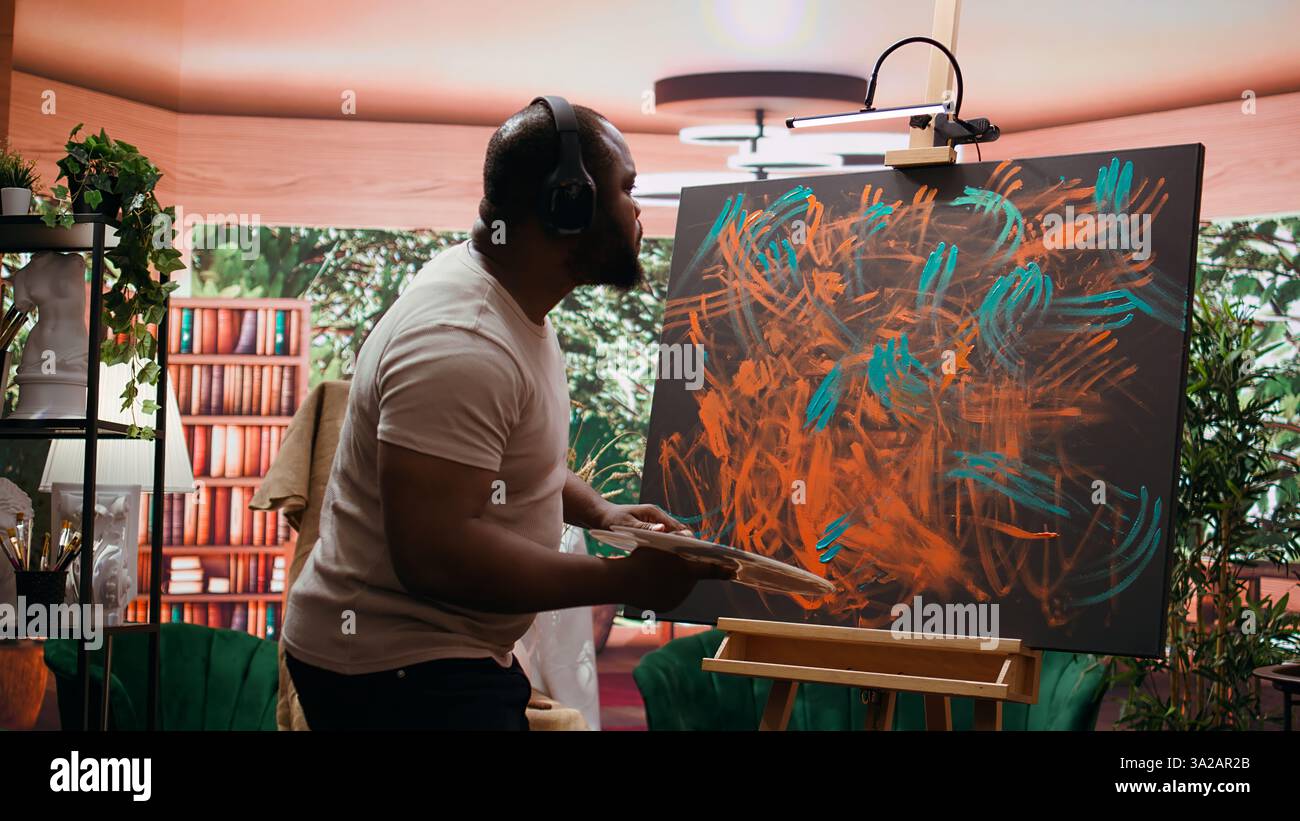 Artist listening to music and creating an abstract painting with his ...