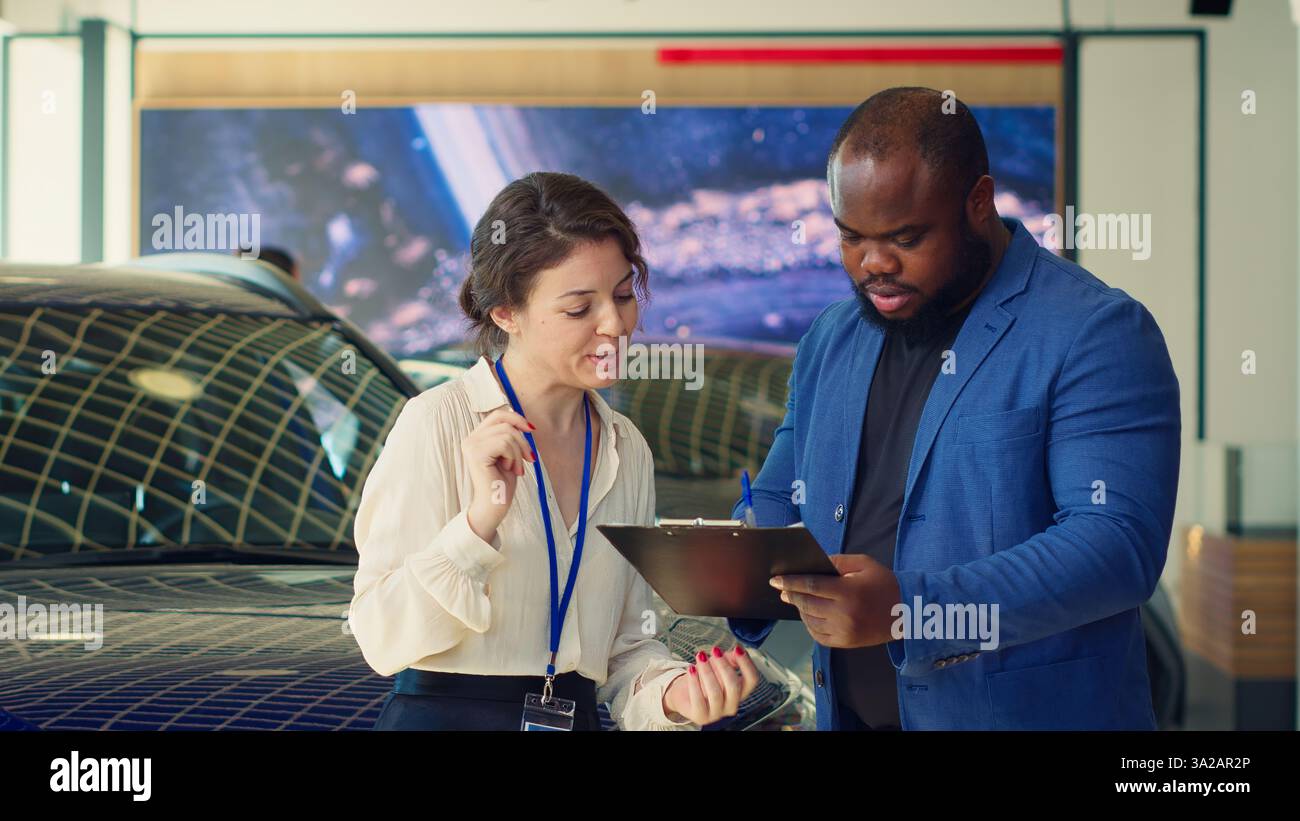 Saleswoman in car dealership signing contract with man after addressing ...