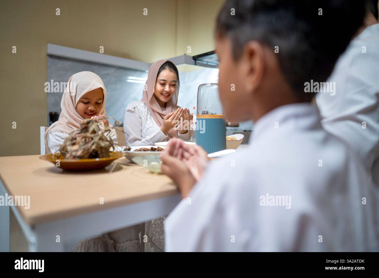 Indonesian Muslim family praying together before eating ketupat rice ...