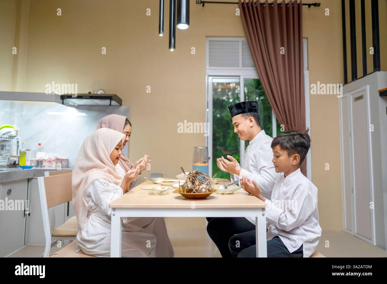 Indonesian Muslim family praying together before eating ketupat rice ...