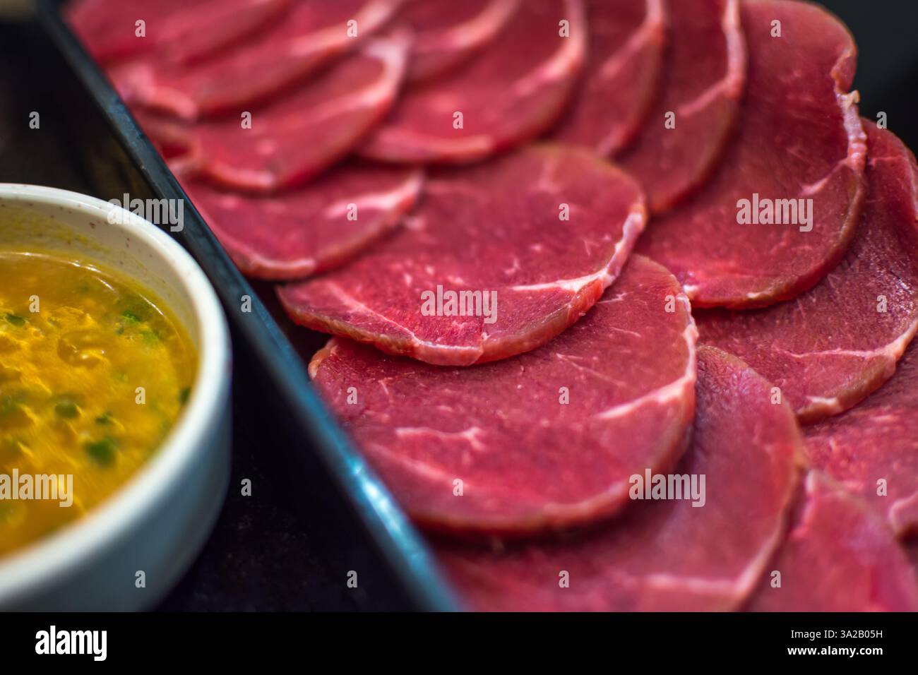 Beef raw meat slides on dish with barbecue sauce at BBQ. yakiniku grill ...