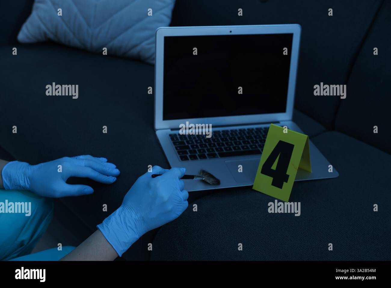 Forensic expert taking fingerprints with brush from laptop at crime ...