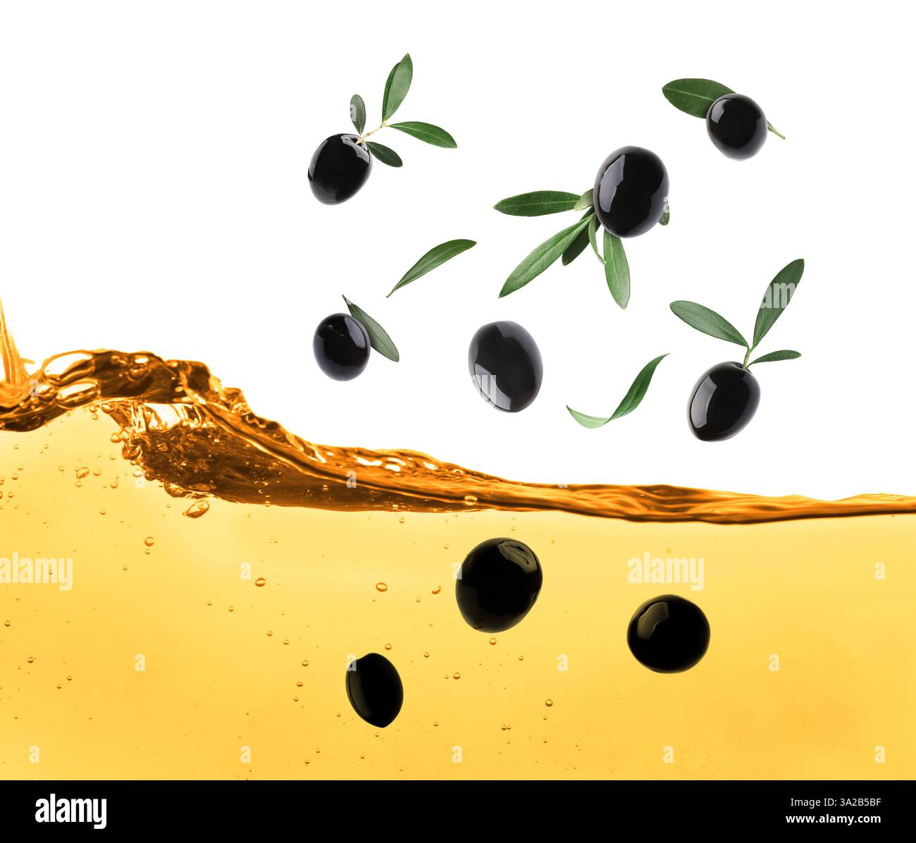 Black olives and green leaves falling into cooking oil on white ...