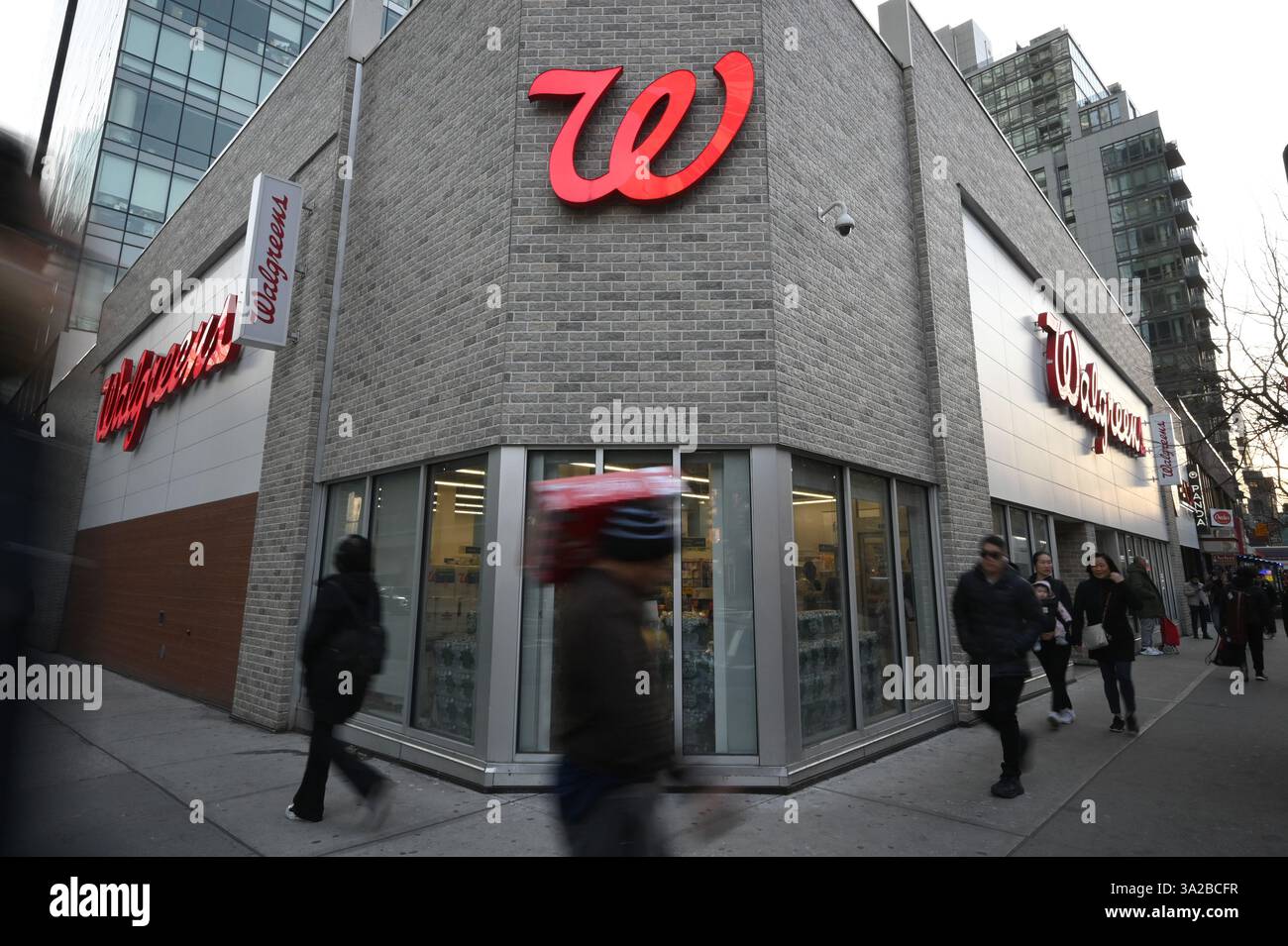 People walk past a Walgreens Pharmacy and retail store in the Queens ...