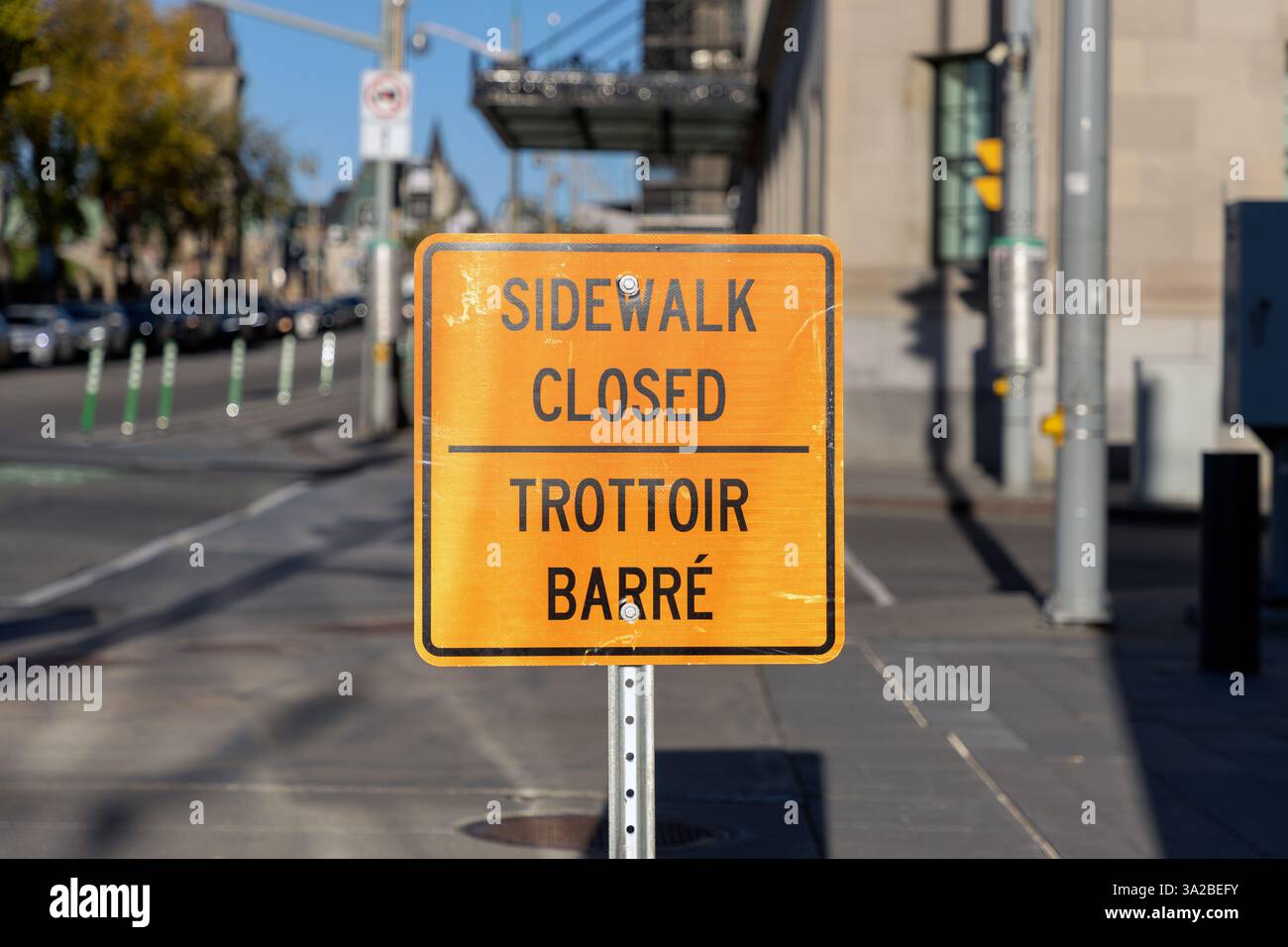 Orange sidewalk closed sign in English and French on road in downtown ...