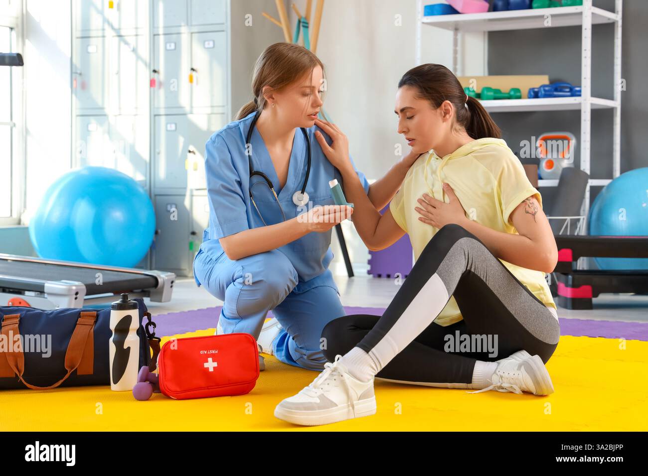 Female doctor with inhaler giving young woman first aid in gym Stock ...