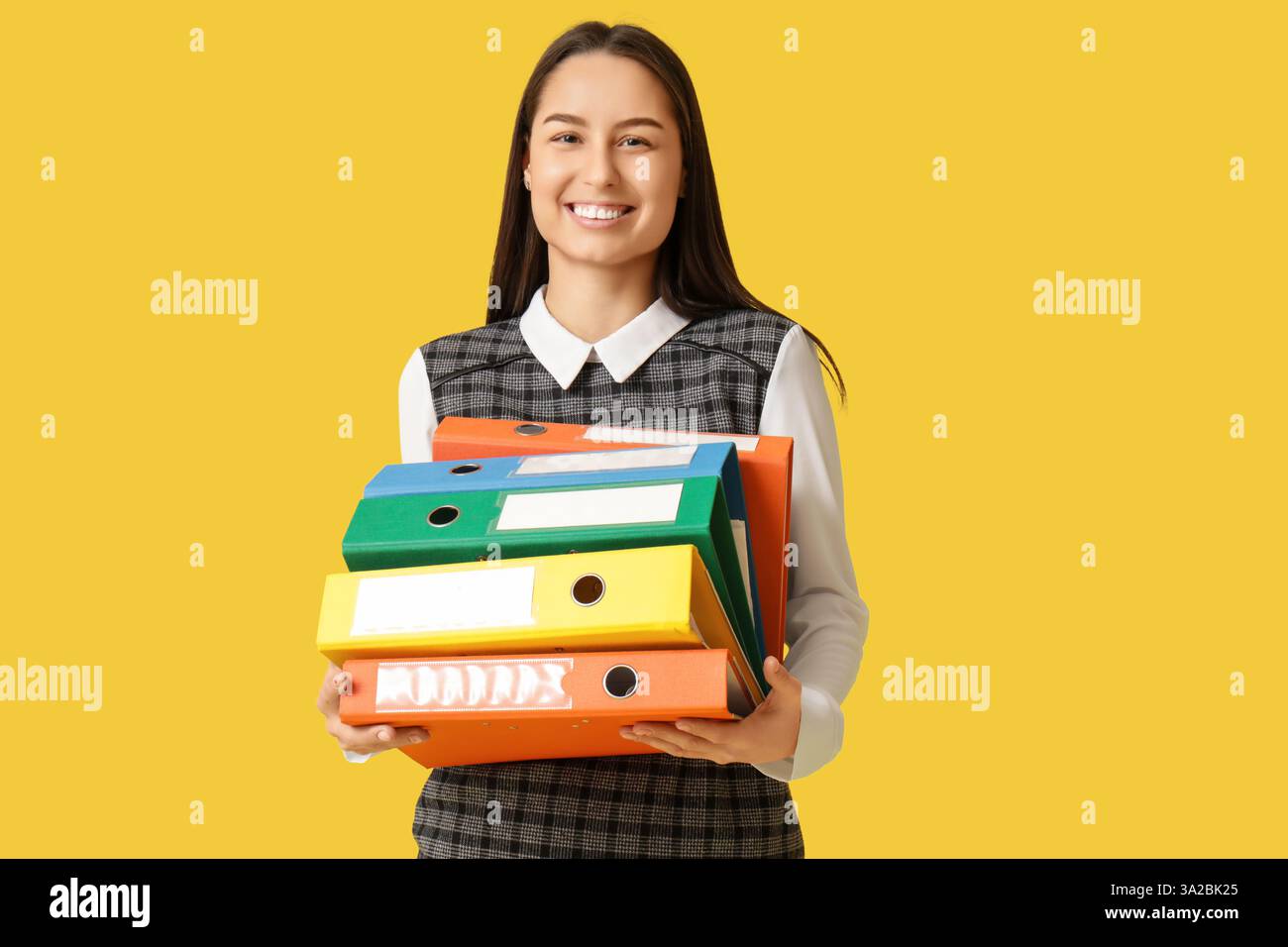 Young secretary holding office folders on yellow background Stock Photo ...