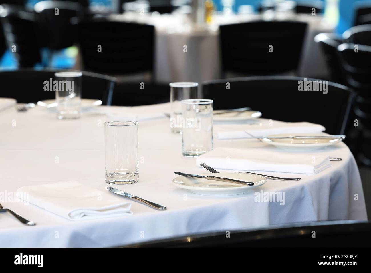 A round table with a white table cloth at a large function centre, set ...