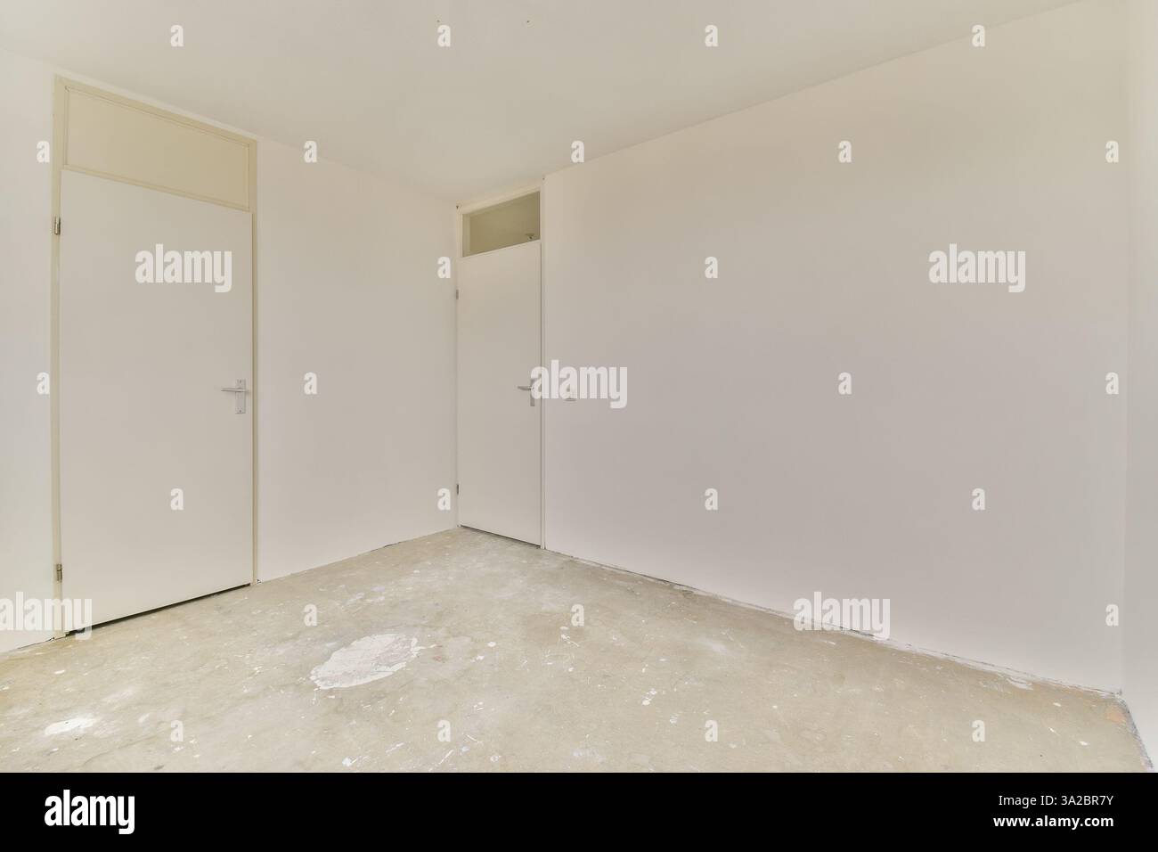 A vacant room featuring plain white walls and a concrete floor ...