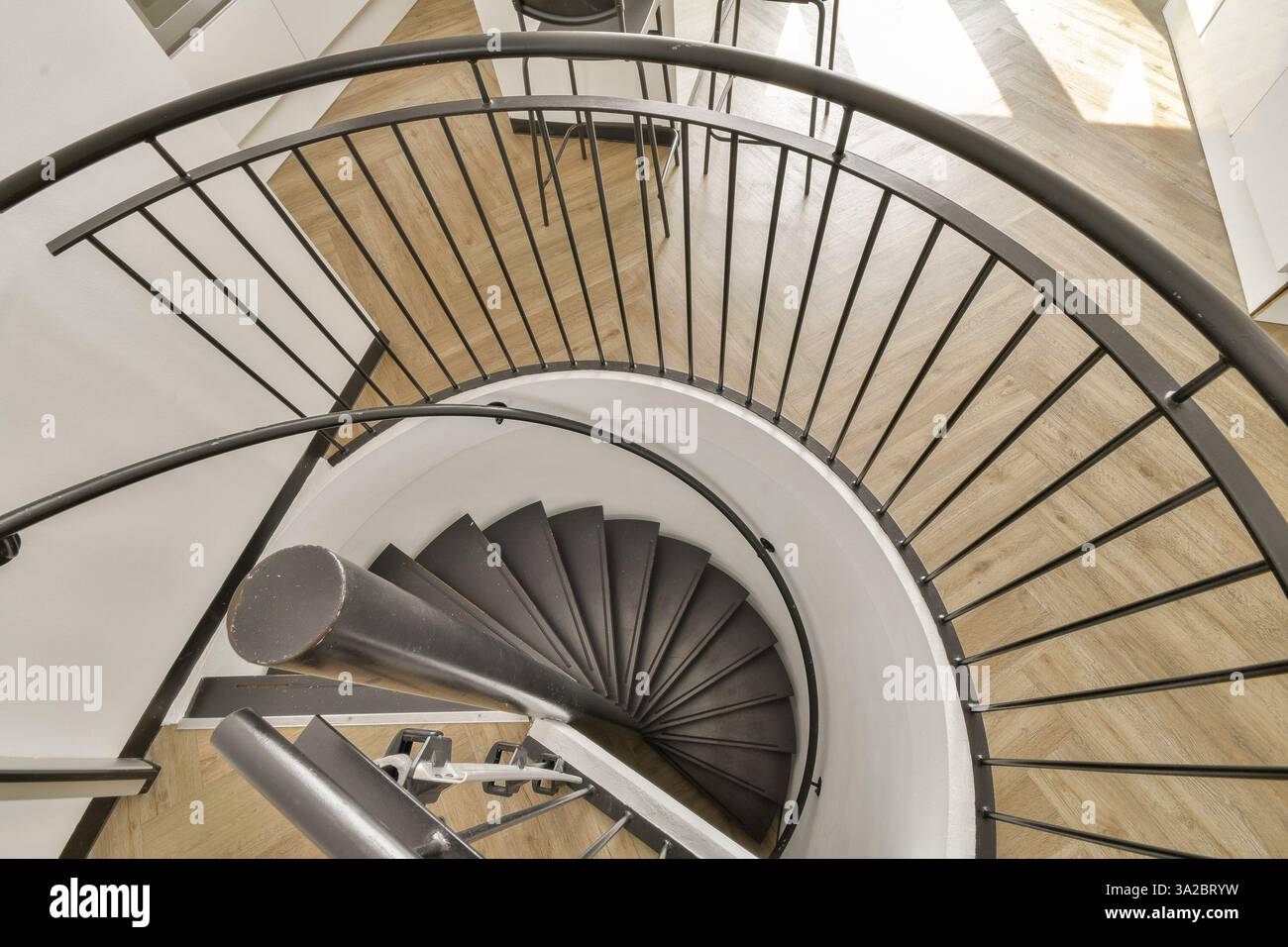 A captivating view of a modern spiral staircase featuring sleek black railings and a light wood ...
