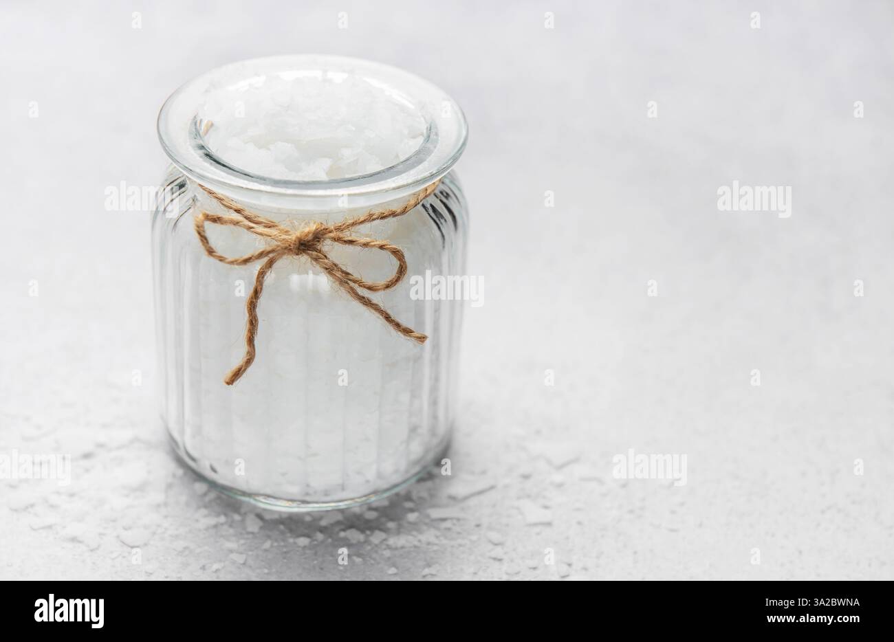 Magnesium chloride flakes stored in a transparent glass jar with a ...