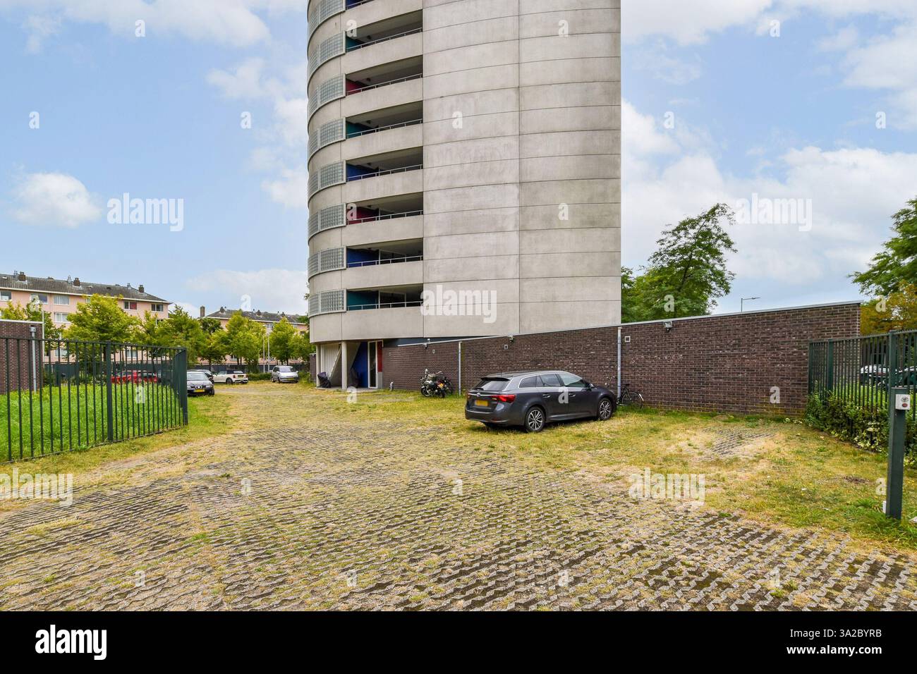 A sleek modern residential building towers over a structured parking ...