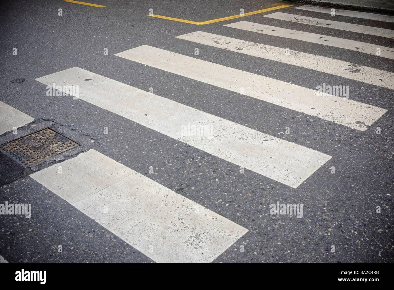Pedestrian crosswalk with white stripes, yellow road markings, and ...