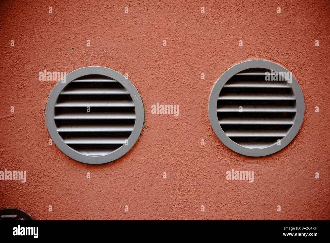 Circular vents integrated into a textured red wall, promoting efficient ...