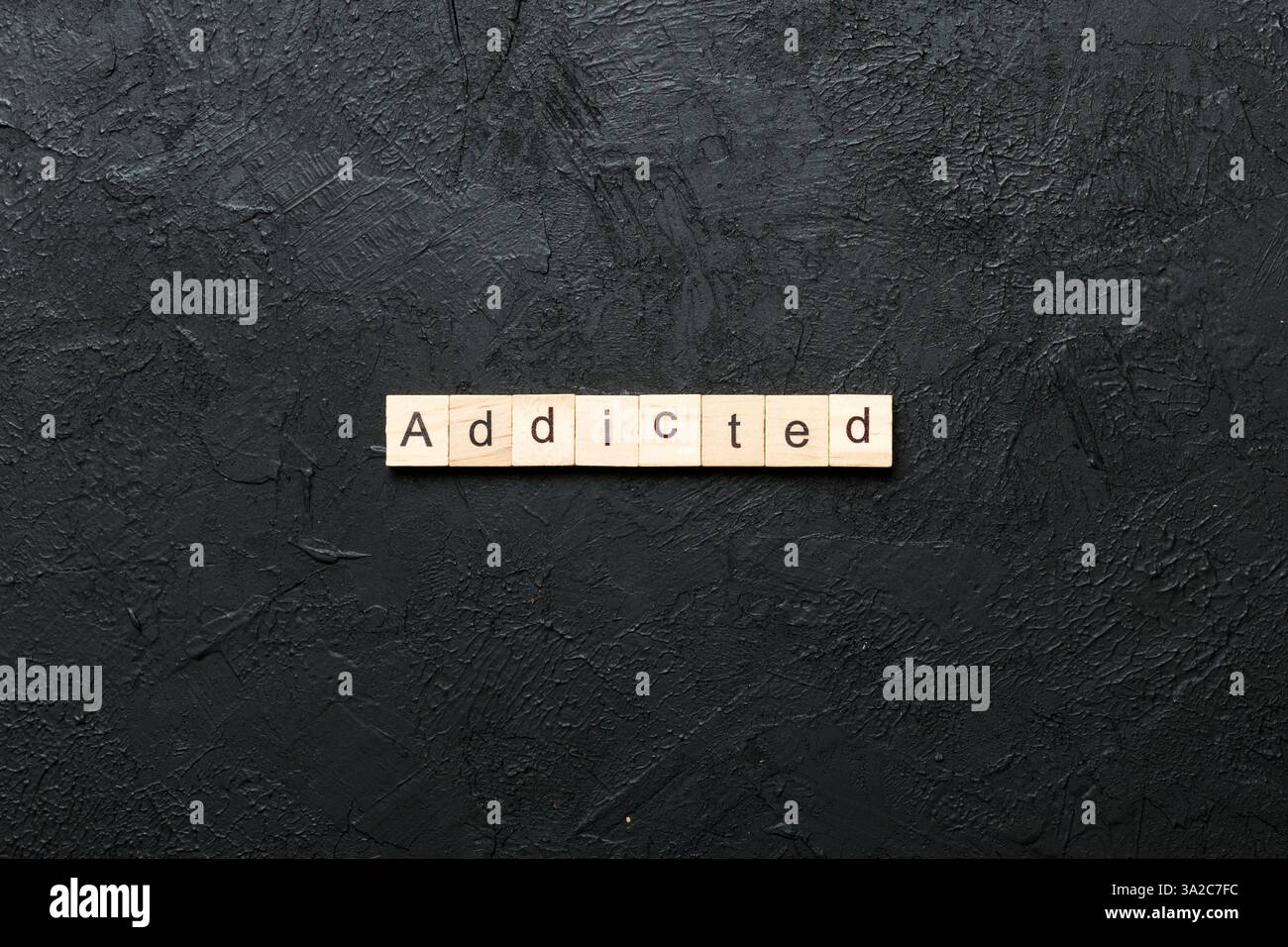 Addicted word written on wood block. Addicted text on cement table for ...