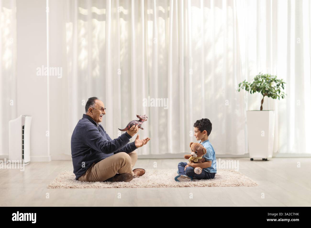Man and boy sitting on a carpet and playing with toys isolated on white ...