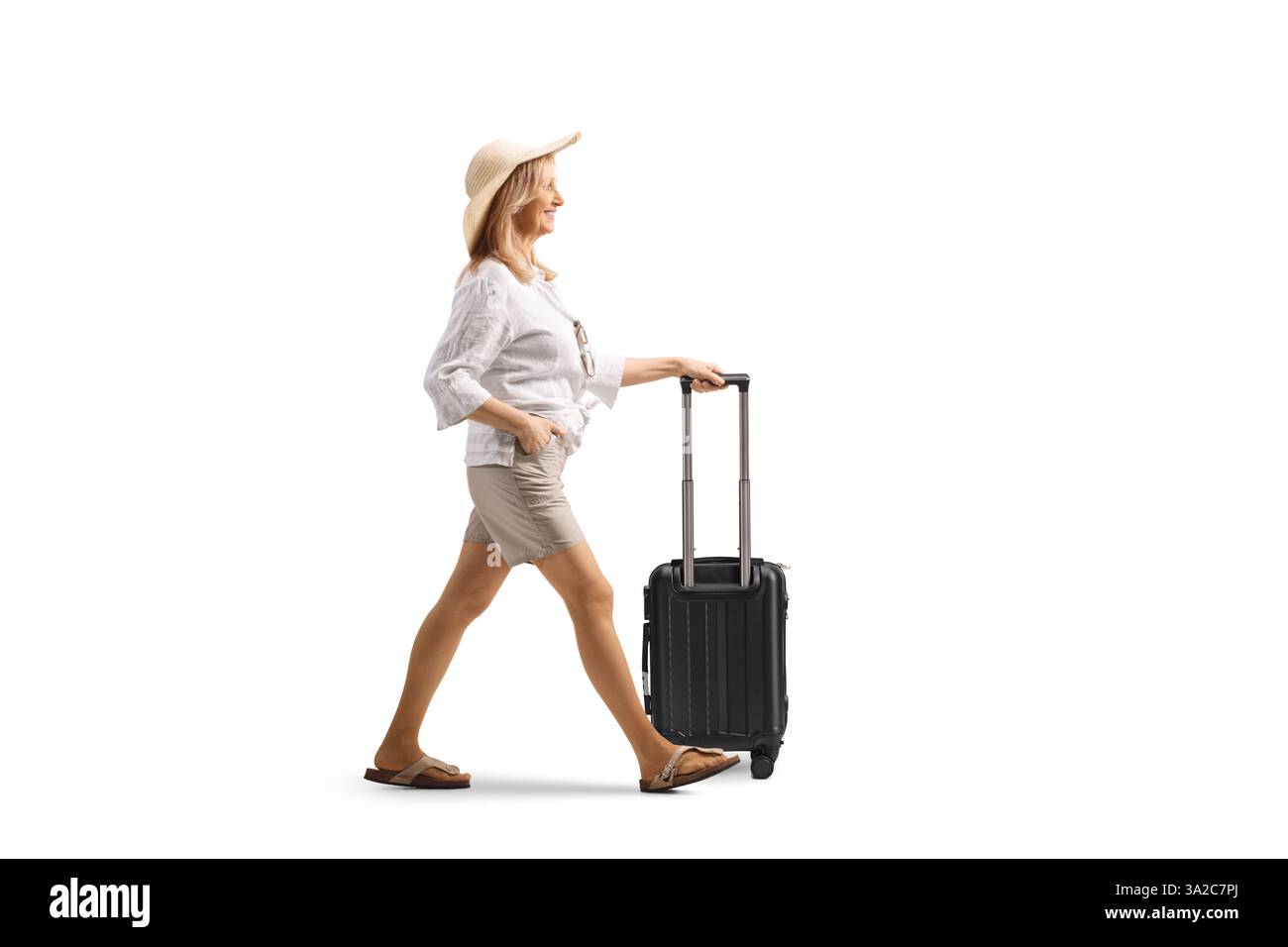 Full length profile shot of a female tourist pulling a suitcase ...