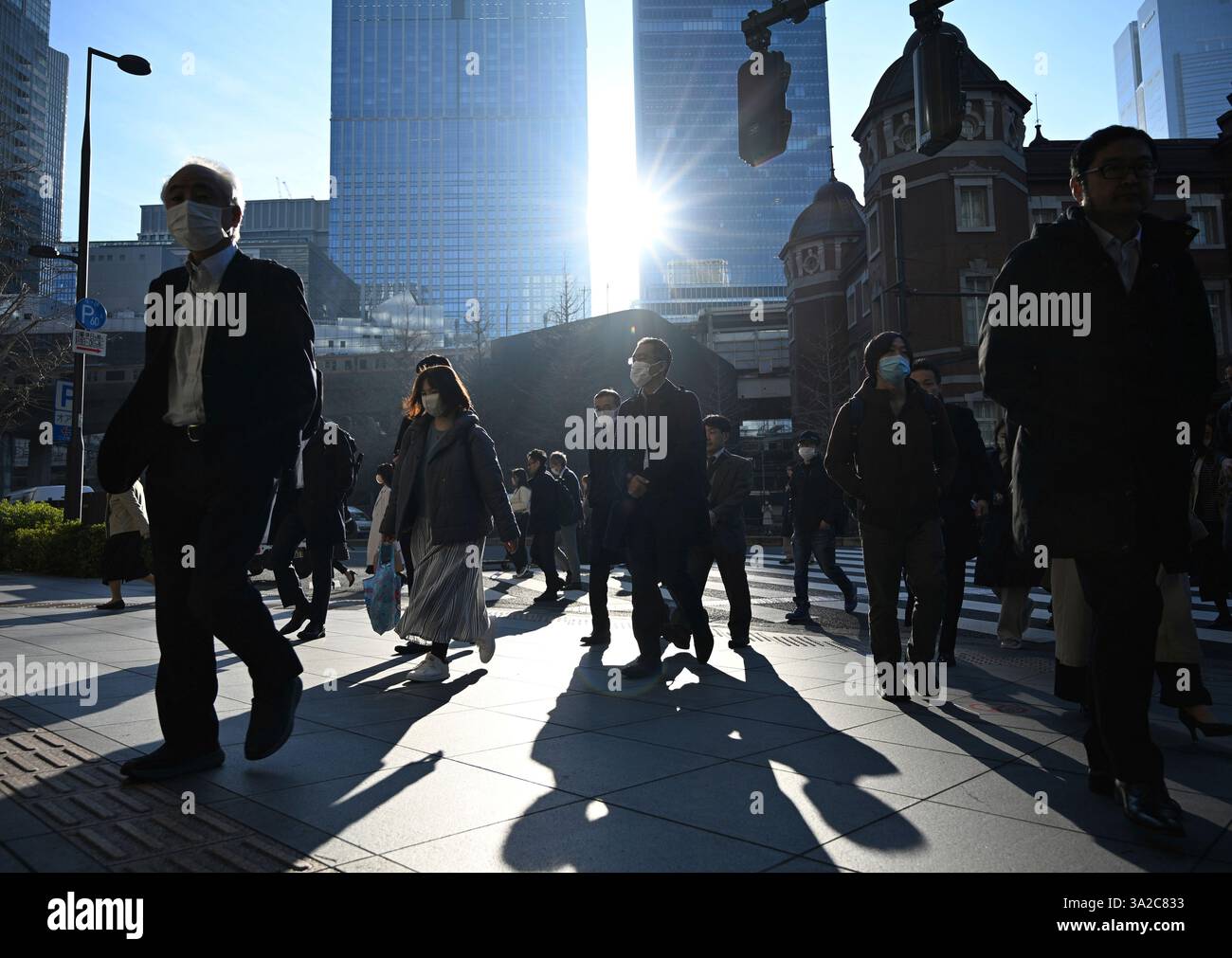 Commuters and others walk in the strong sunlight in near Tokyo Station ...