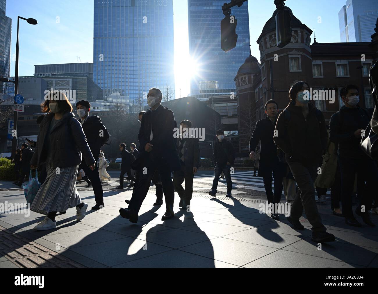 Commuters and others walk in the strong sunlight in near Tokyo Station ...