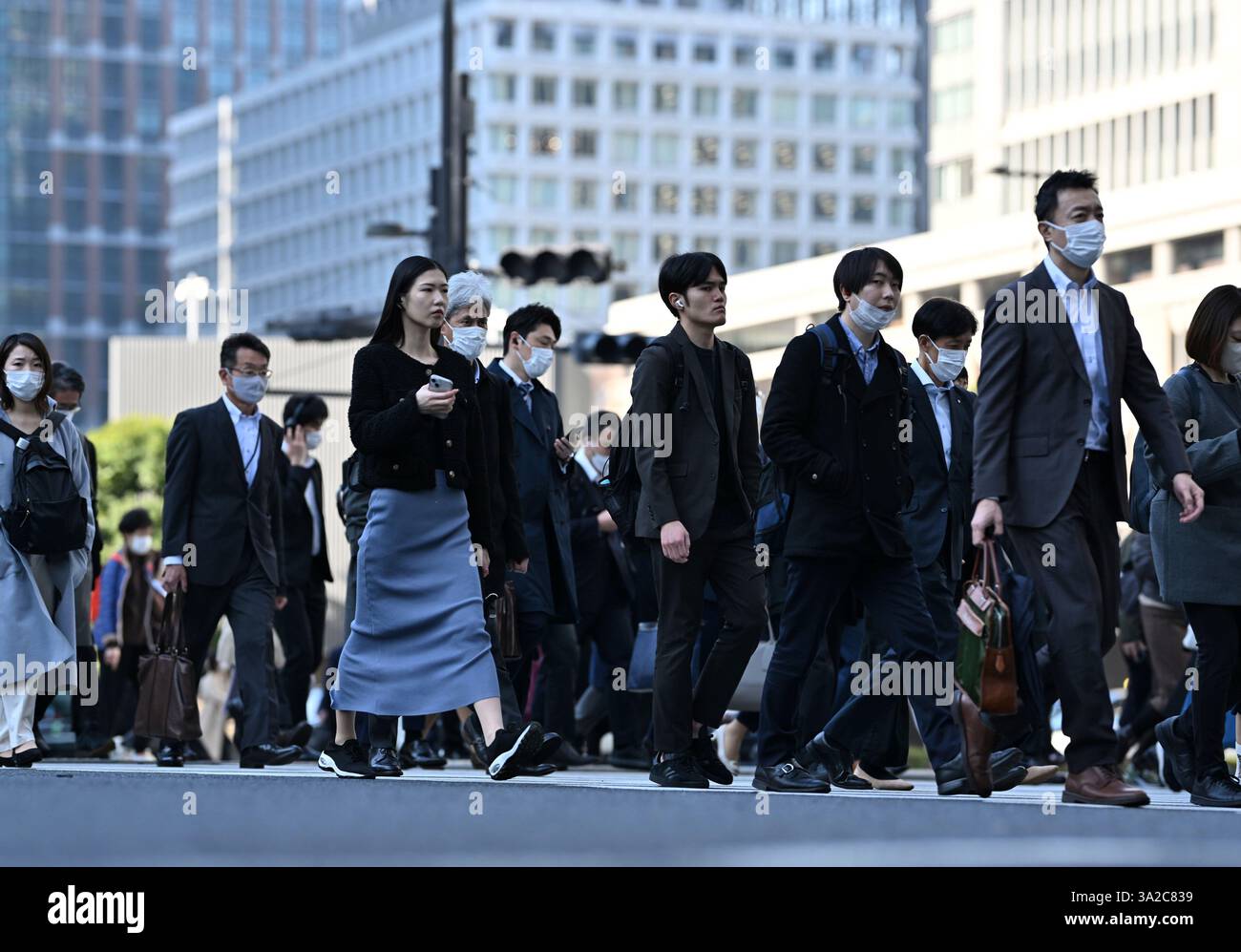 Commuters and others walk in the strong sunlight in near Tokyo Station in Chiyoda Ward, Tokyo ...